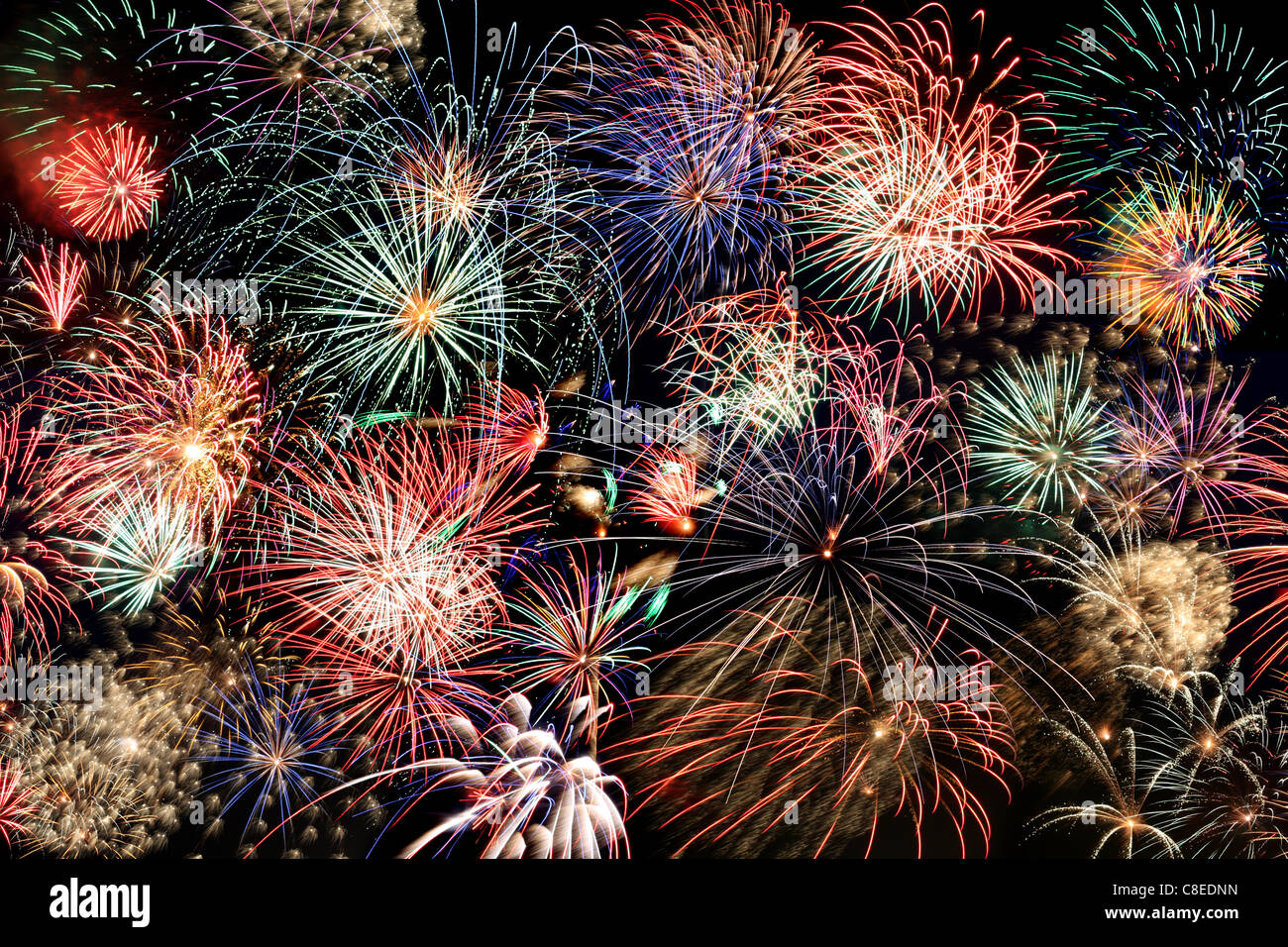Multiple bursts of multicolored fireworks fill the horizontal frame ...