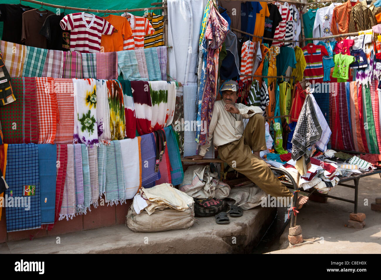 Stallholder selling clothes and sari fabrics and other textiles at ...