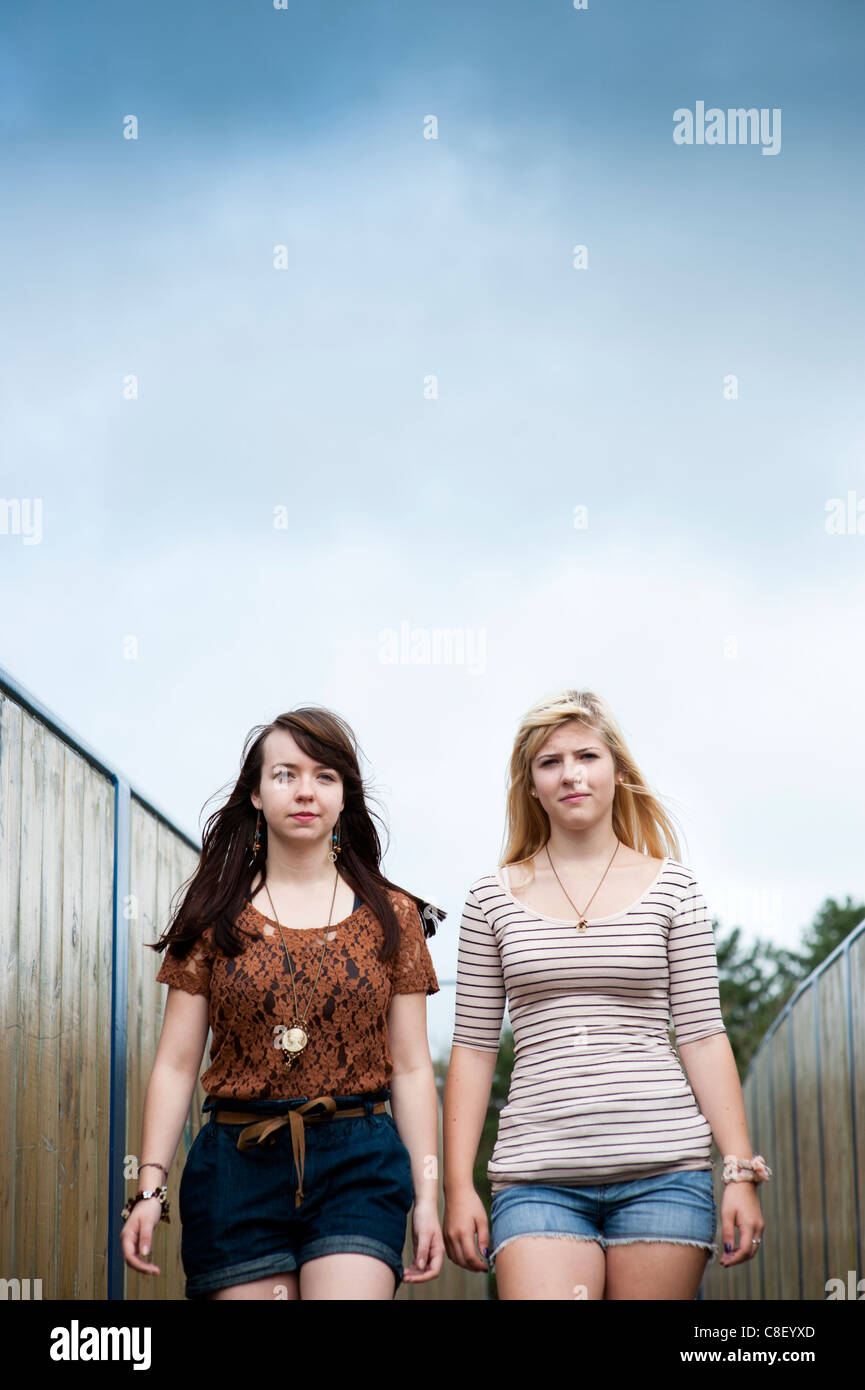 Two 16 17 year old teenage girls, outdoors, walking towards the camera ...
