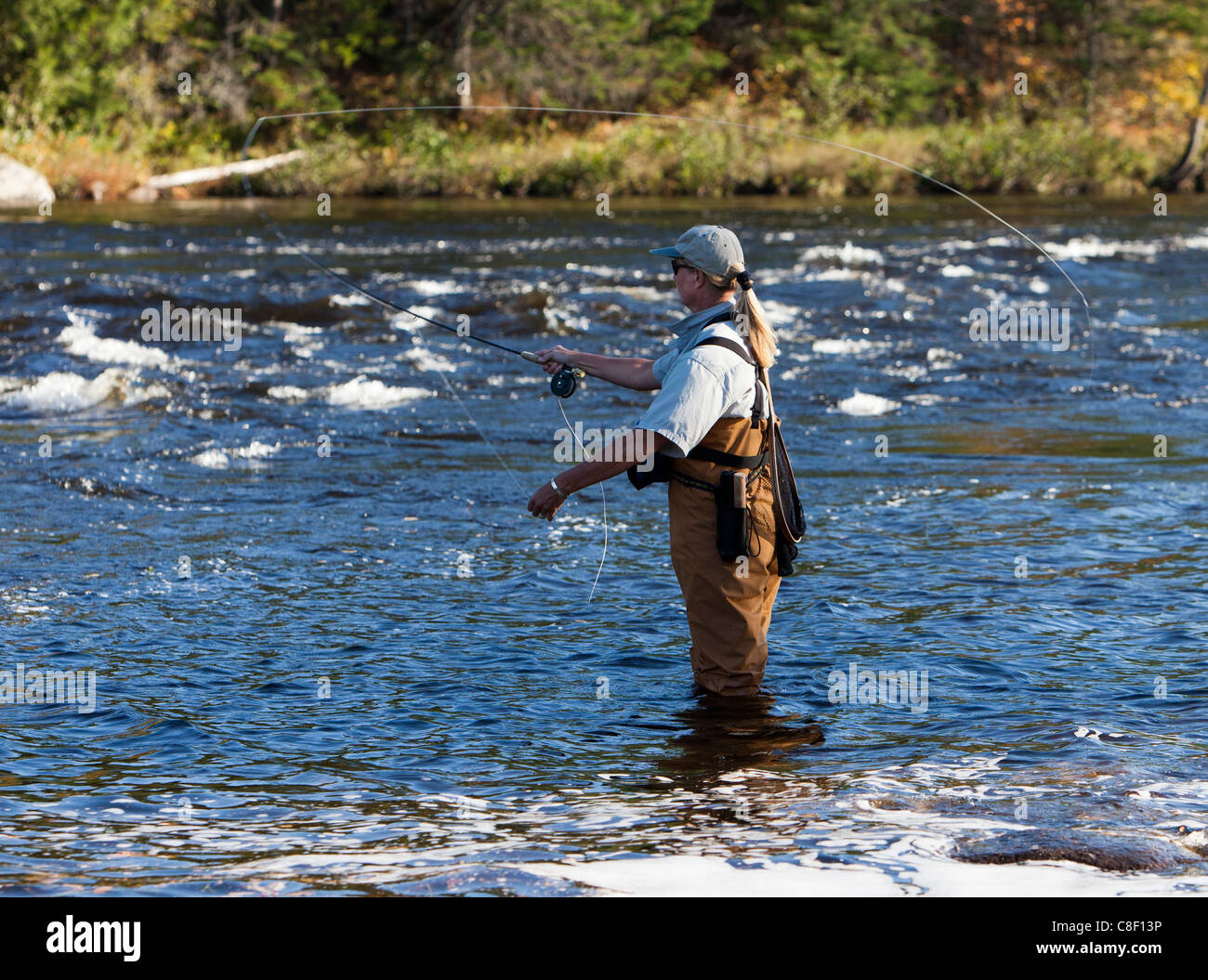 A woman fly fishing in a river with rapids Stock Photo - Alamy