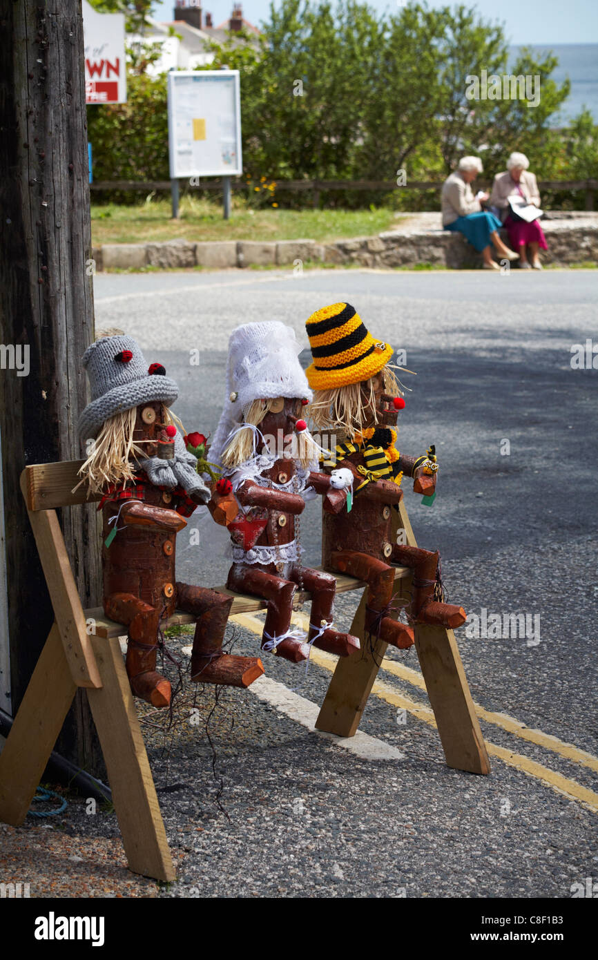 Three wooden characters sat on bench with two senior ladies sat on wall ...