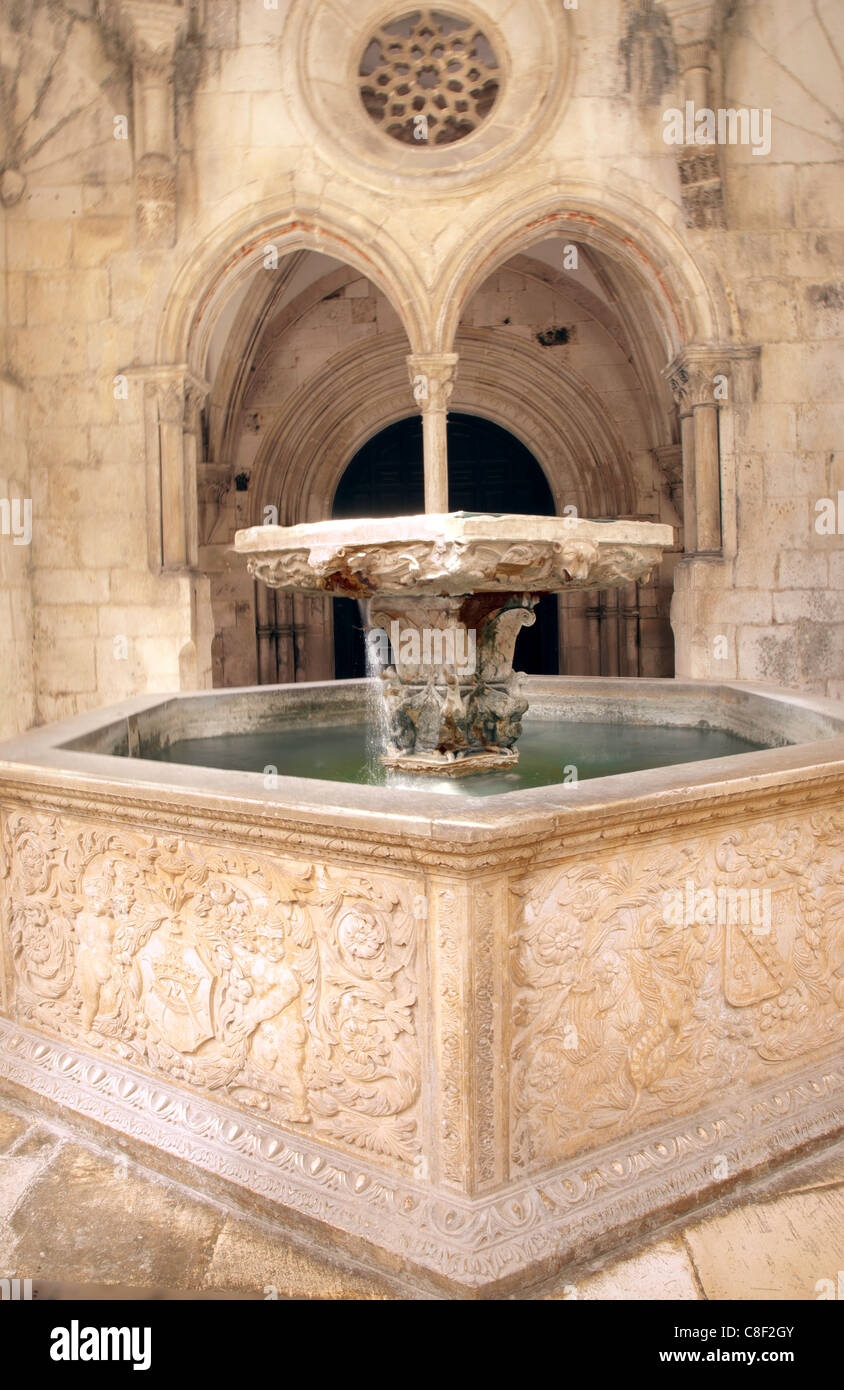 Monastery at Alcobaca, a stone carved fountain, arches and a round ...