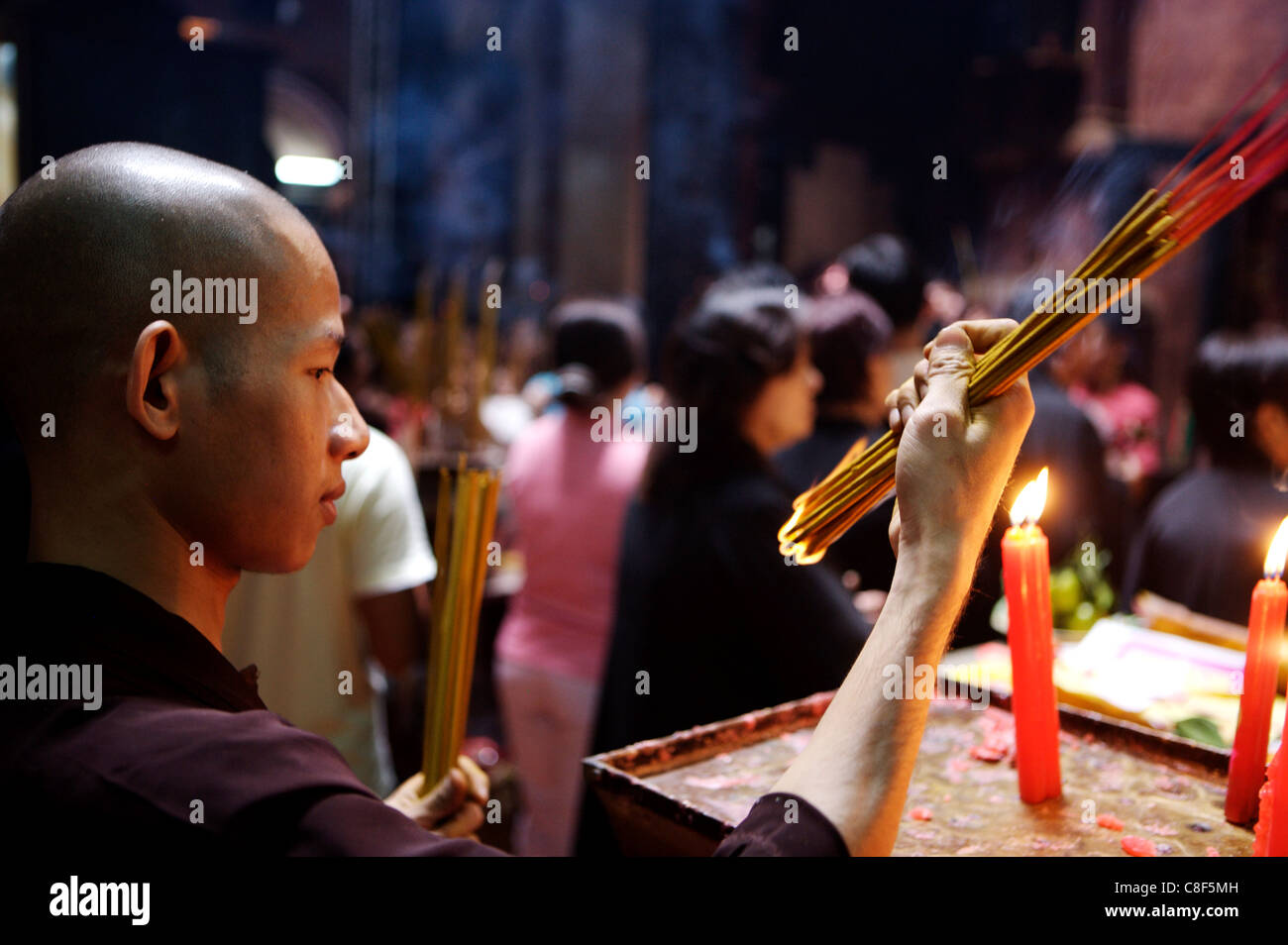 Monk lighting joss sticks during ceremony in a Buddhist temple, Ho Chi ...