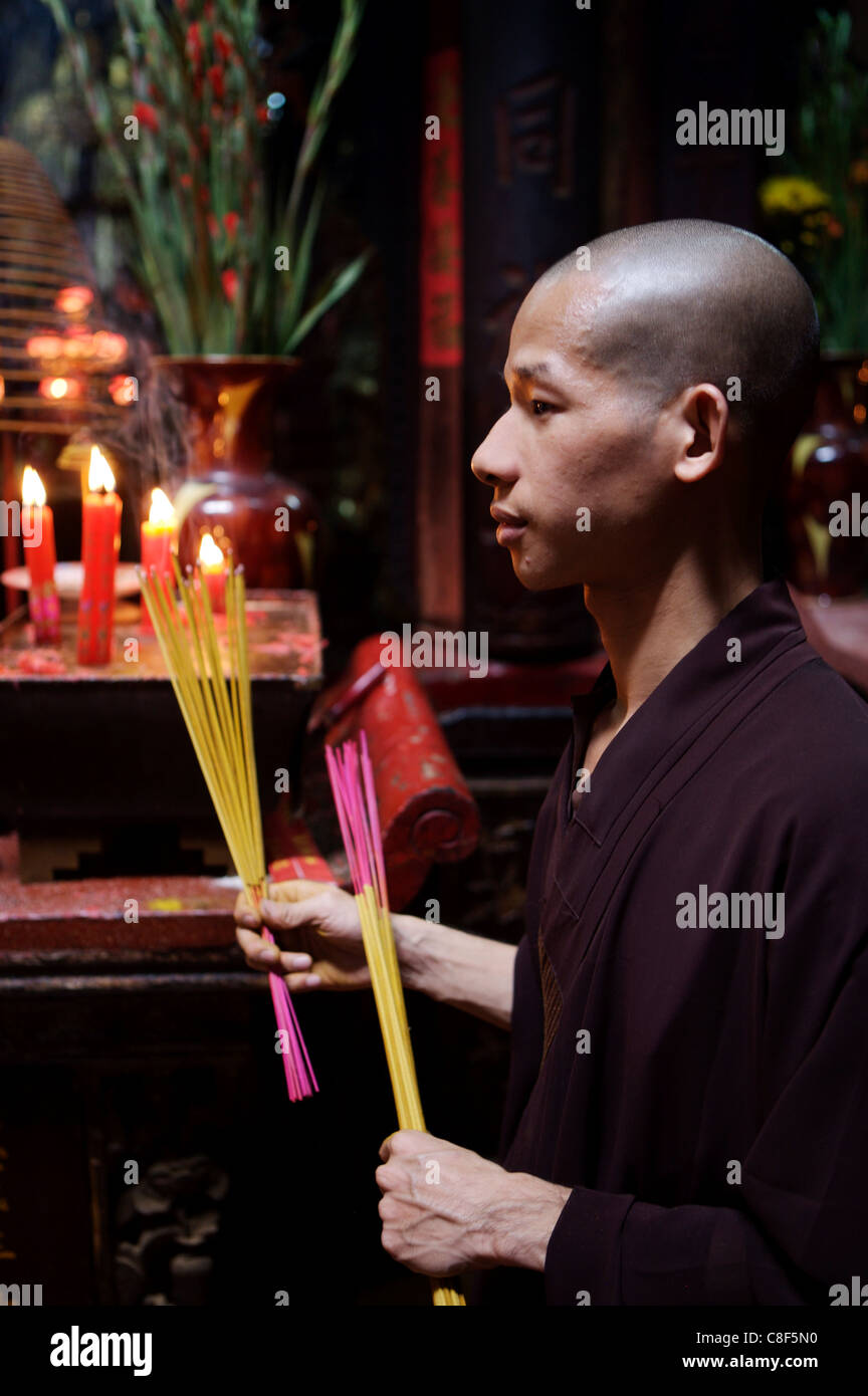 Monk with joss sticks during ceremony in a Buddhist temple, Ho Chi Min ...