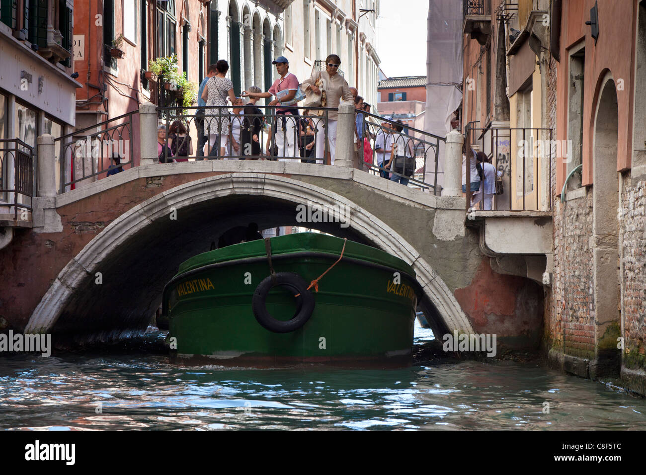 a barge passing under a small bridge with tourists on the bridge in ...