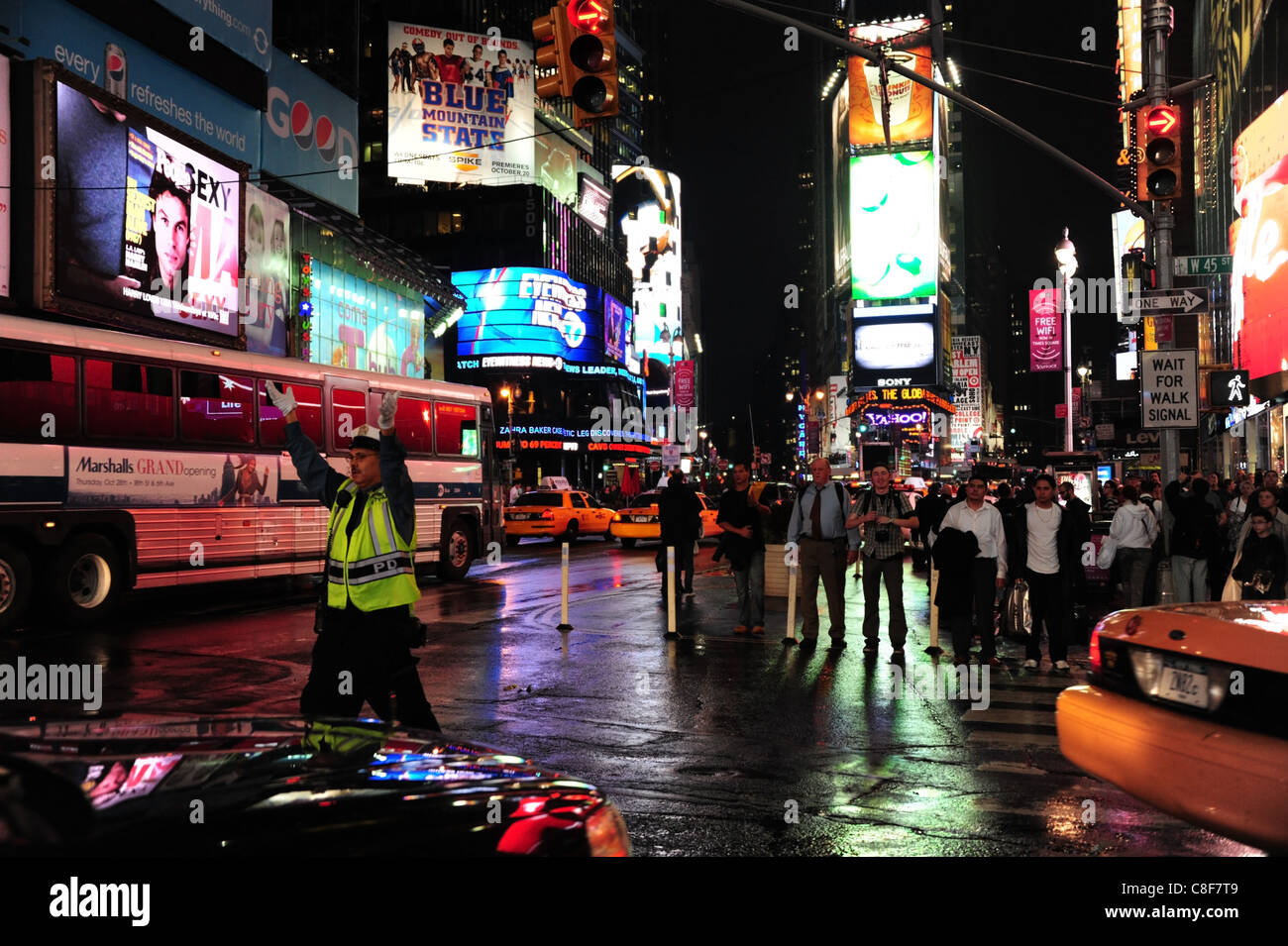 Night shot yellow jacket policeman hands raised directing traffic West ...
