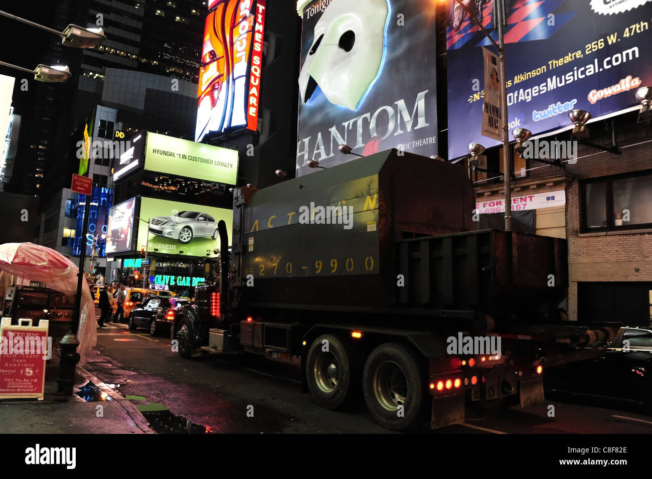 Night shot green Action garbage truck, below theatre billboards, wet ...