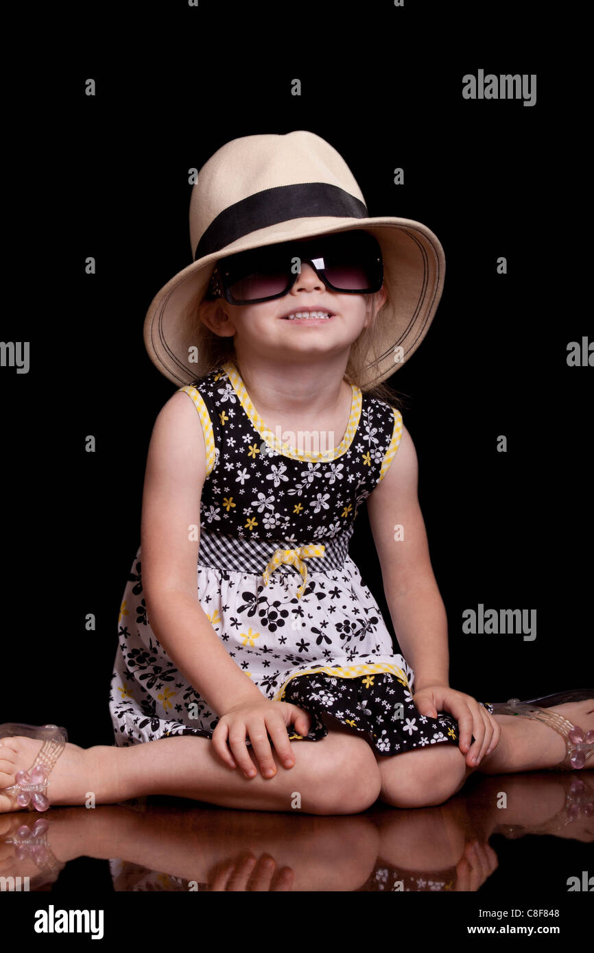 A nervous child poses for the camera with her hat and sunglasses Stock ...