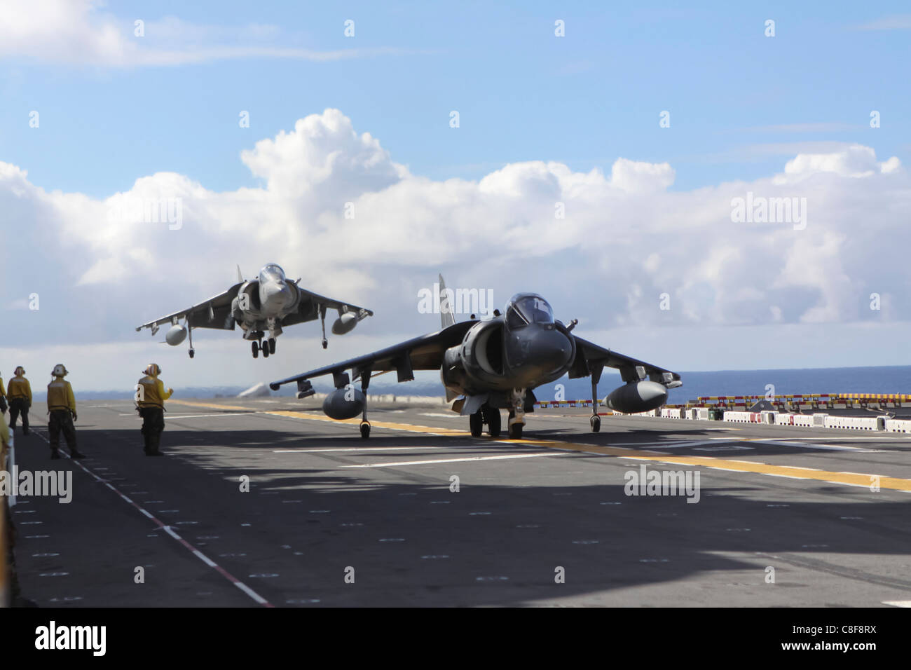 As one AV-8B Harrier prepares for takeoff (foreground), another ...