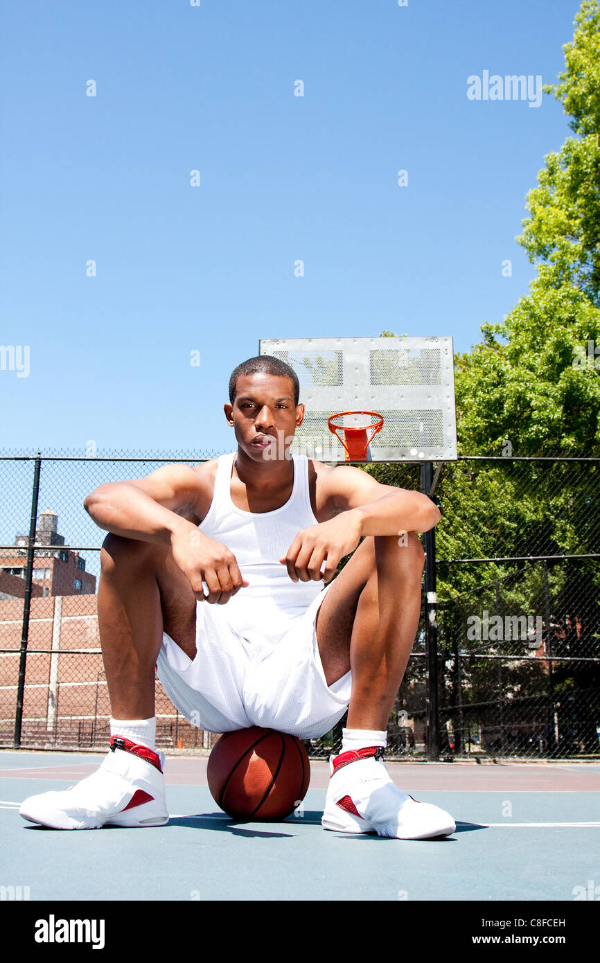 Basketball player sitting on ball Stock Photo - Alamy