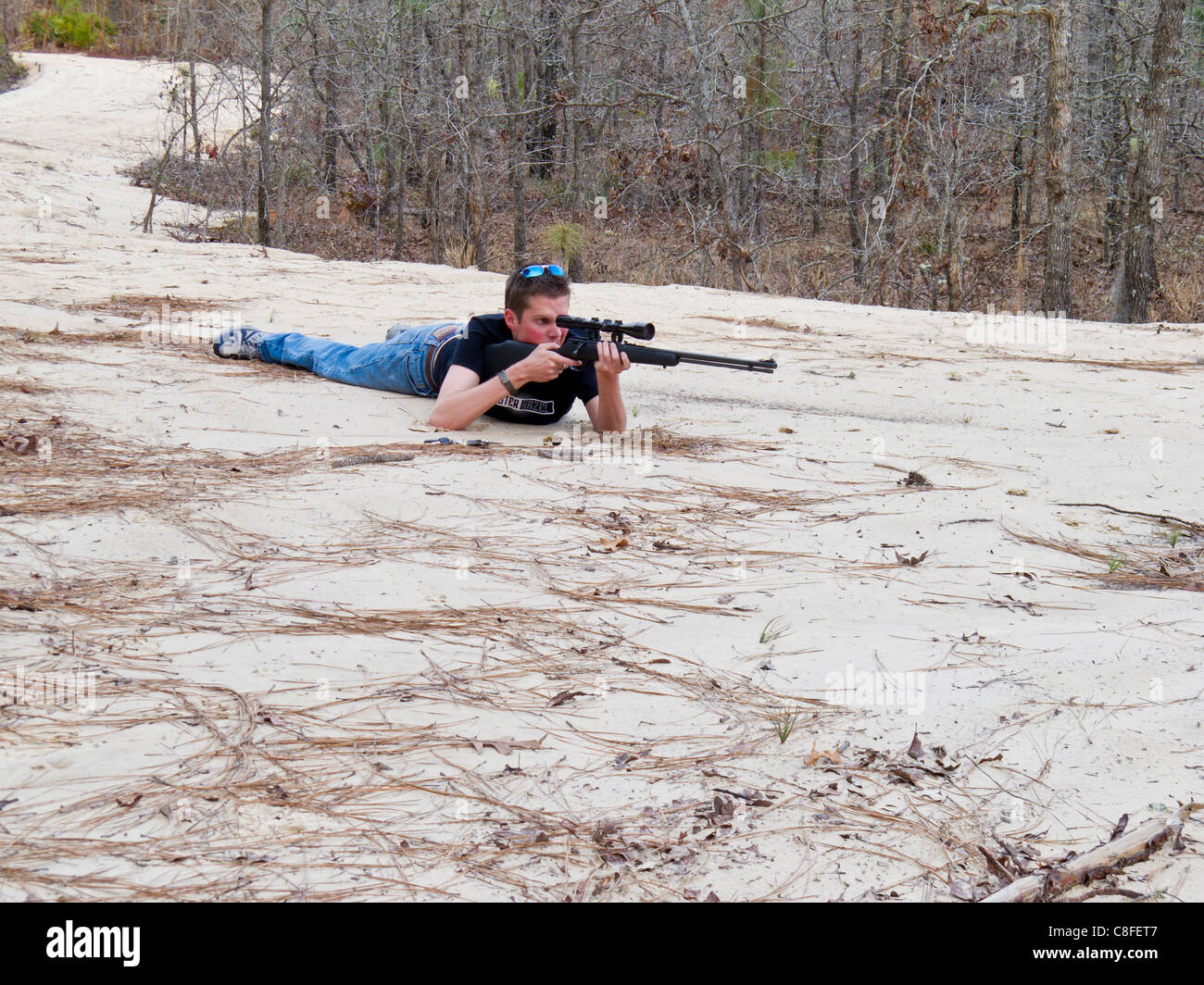 Teen male lying on ground shooting .22 caliber rifle with scope in ...