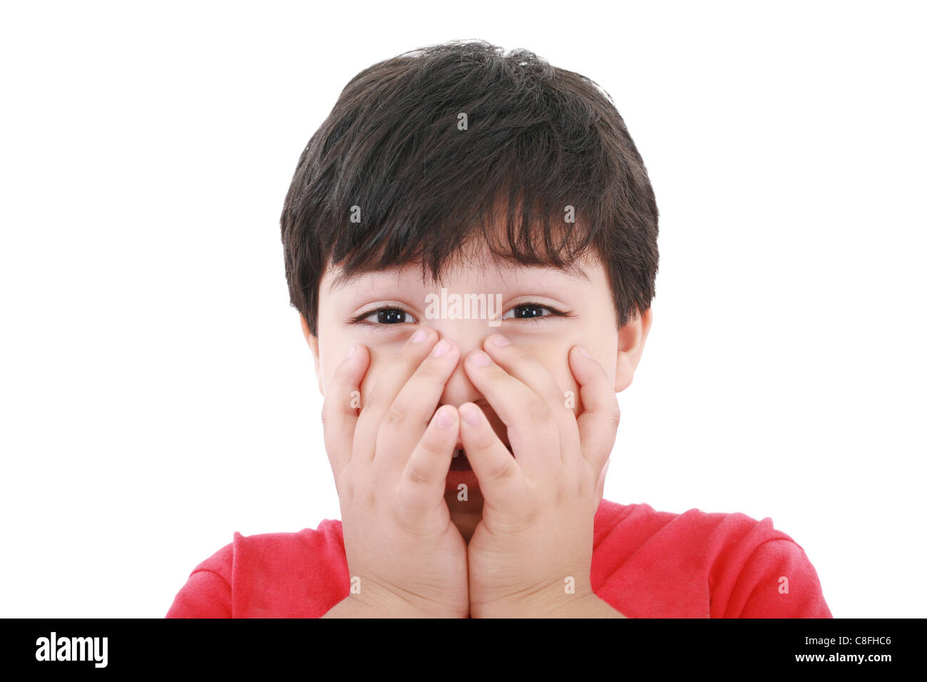 Preschool aged boy with his hand/fists over his mouth; looking ...