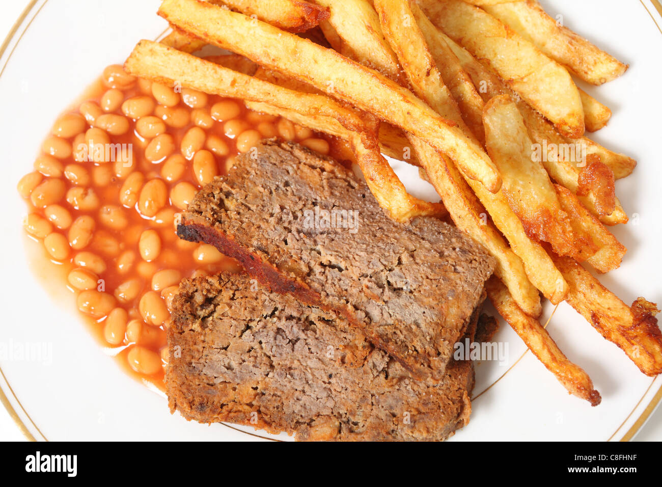 A plate of meatloaf served with baked beans and chips or french fries ...