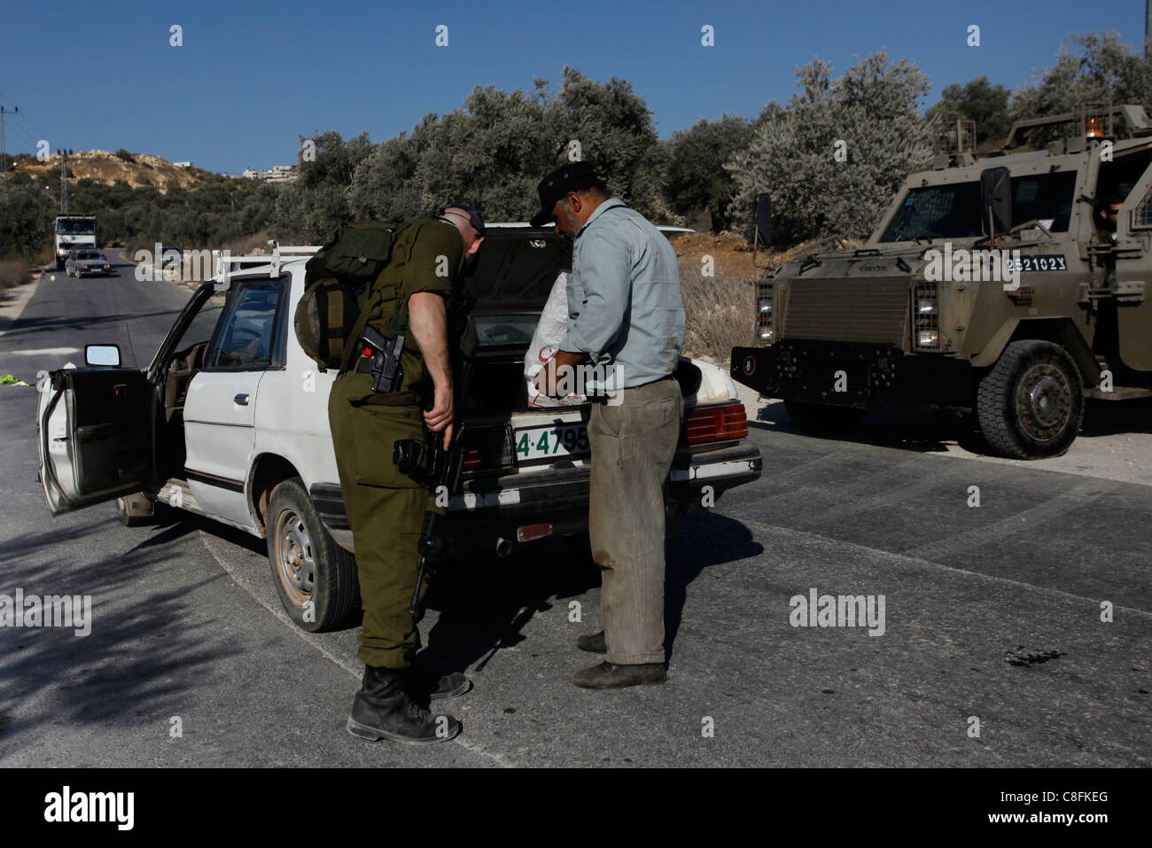 An Israeli soldier checks the trunk of a Palestinian car at a military ...