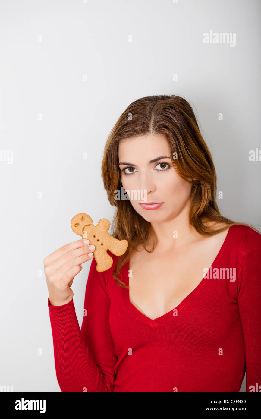 Sad young woman holding an angry gingerbread man cookie Stock Photo - Alamy