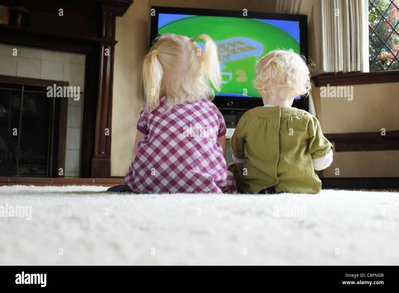 siblings watching television together sitting on a rug Stock Photo - Alamy