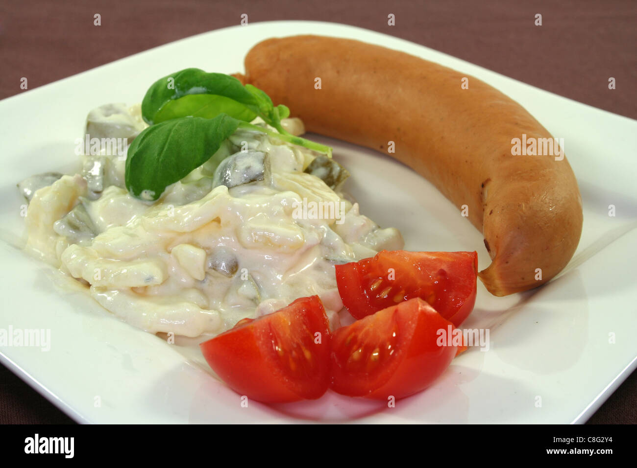 Bockwurst with potato salad, tomato and basil Stock Photo - Alamy