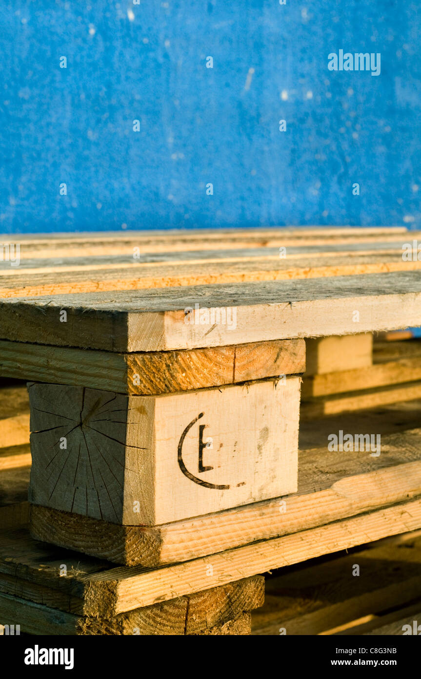 A pile of empty wooden pallets stacked against a wall Stock Photo - Alamy