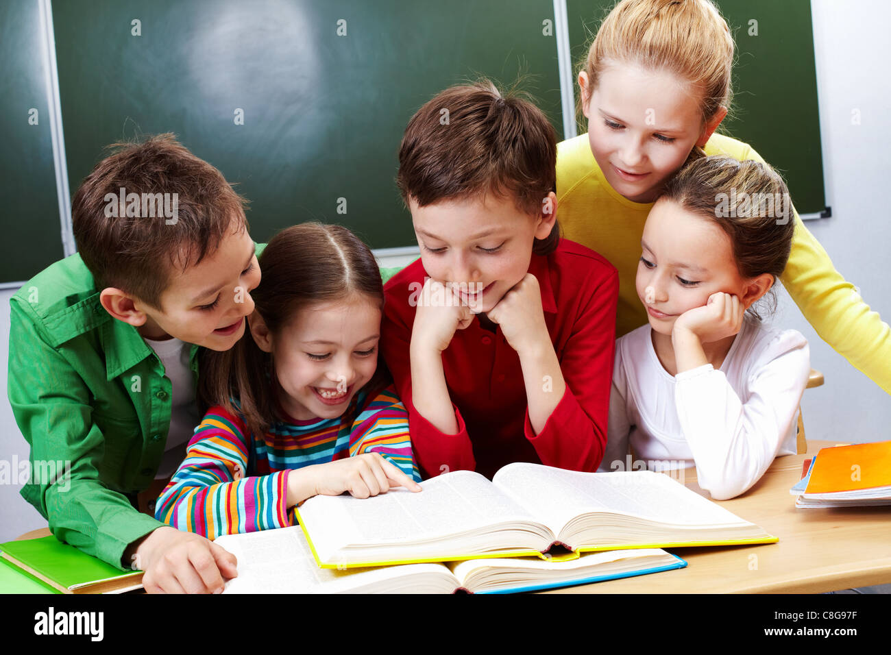 Portrait of friendly group reading book in classroom Stock Photo - Alamy