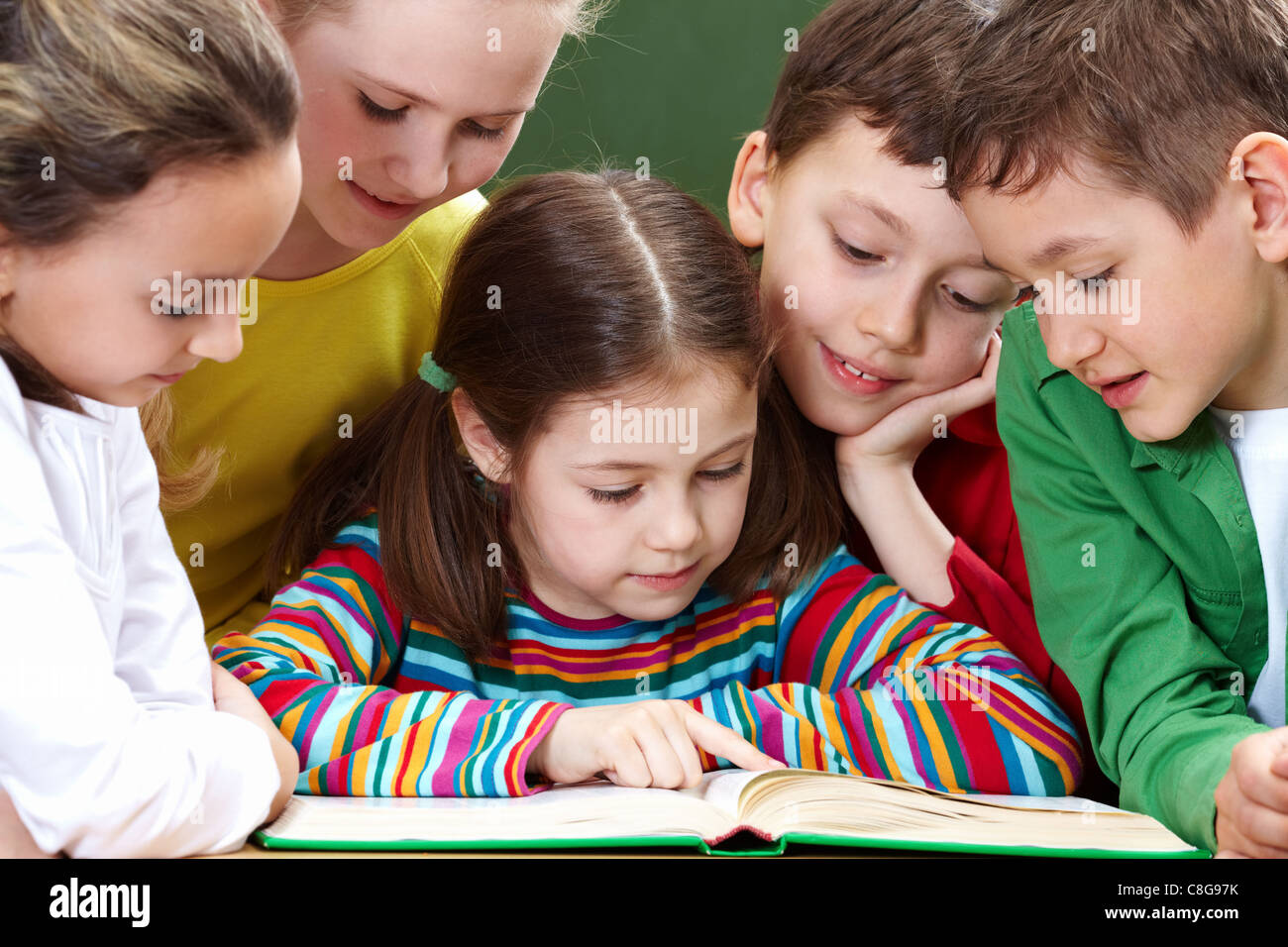 Portrait of friendly group reading book in classroom Stock Photo - Alamy