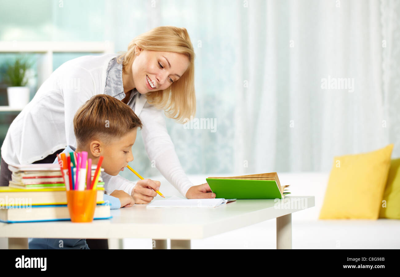 Portrait of smart tutor with pencil correcting mistakes in pupil’s ...