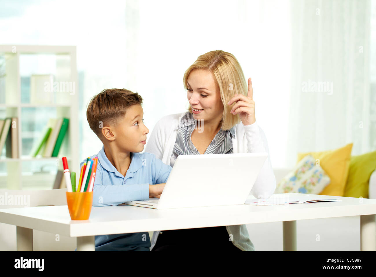 Portrait of pretty tutor and diligent pupil discussing ideas while ...