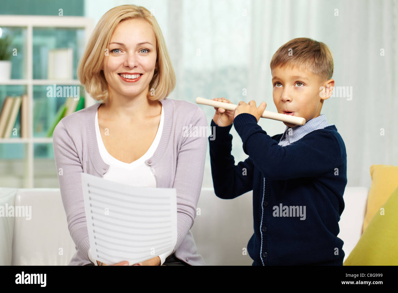 Portrait of happy pupil playing the flute with charming tutor near by ...
