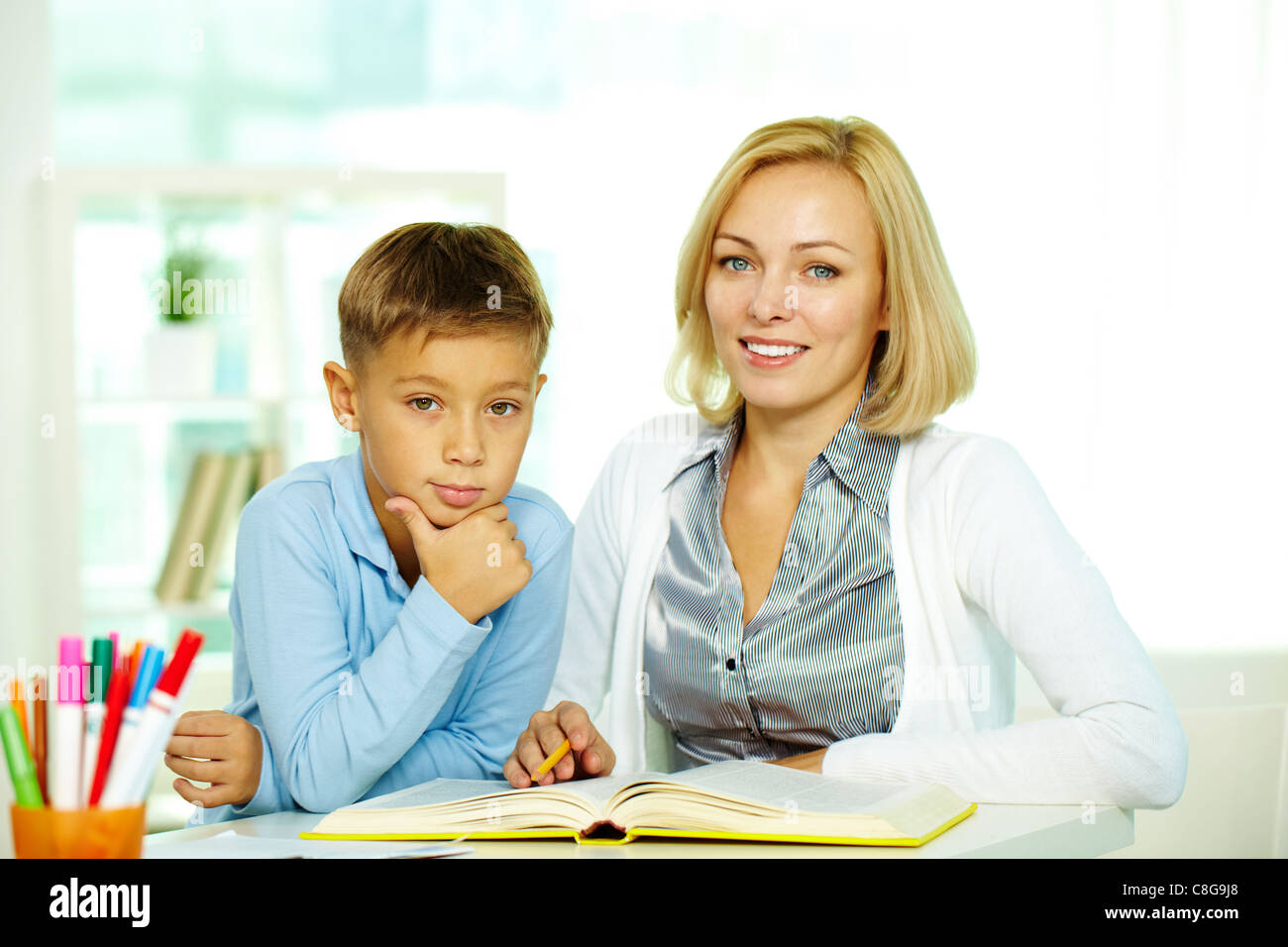 Portrait of pretty tutor and diligent pupil looking at camera with ...