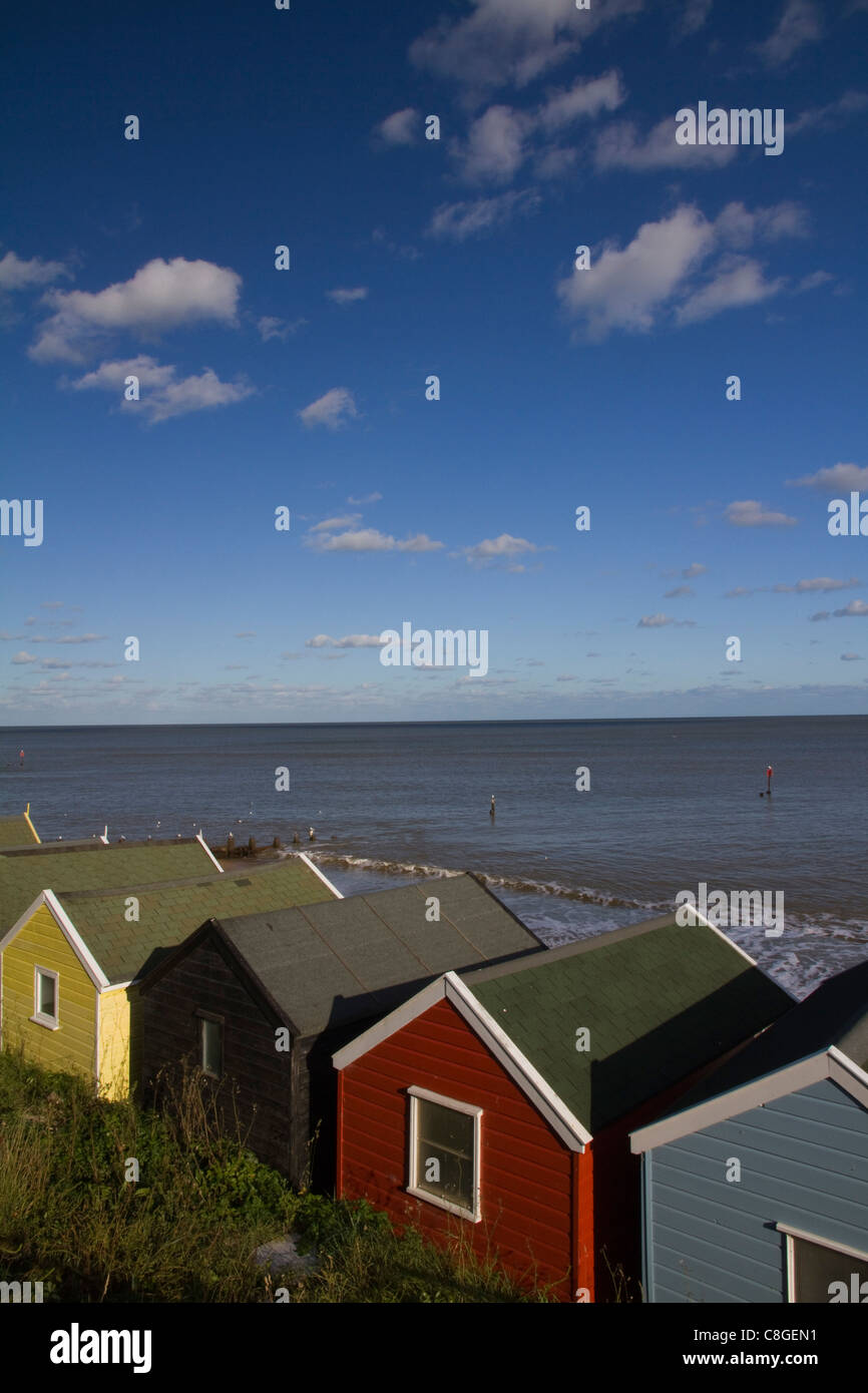 Colourful beach huts look out over the sea under a bright blue sky at ...