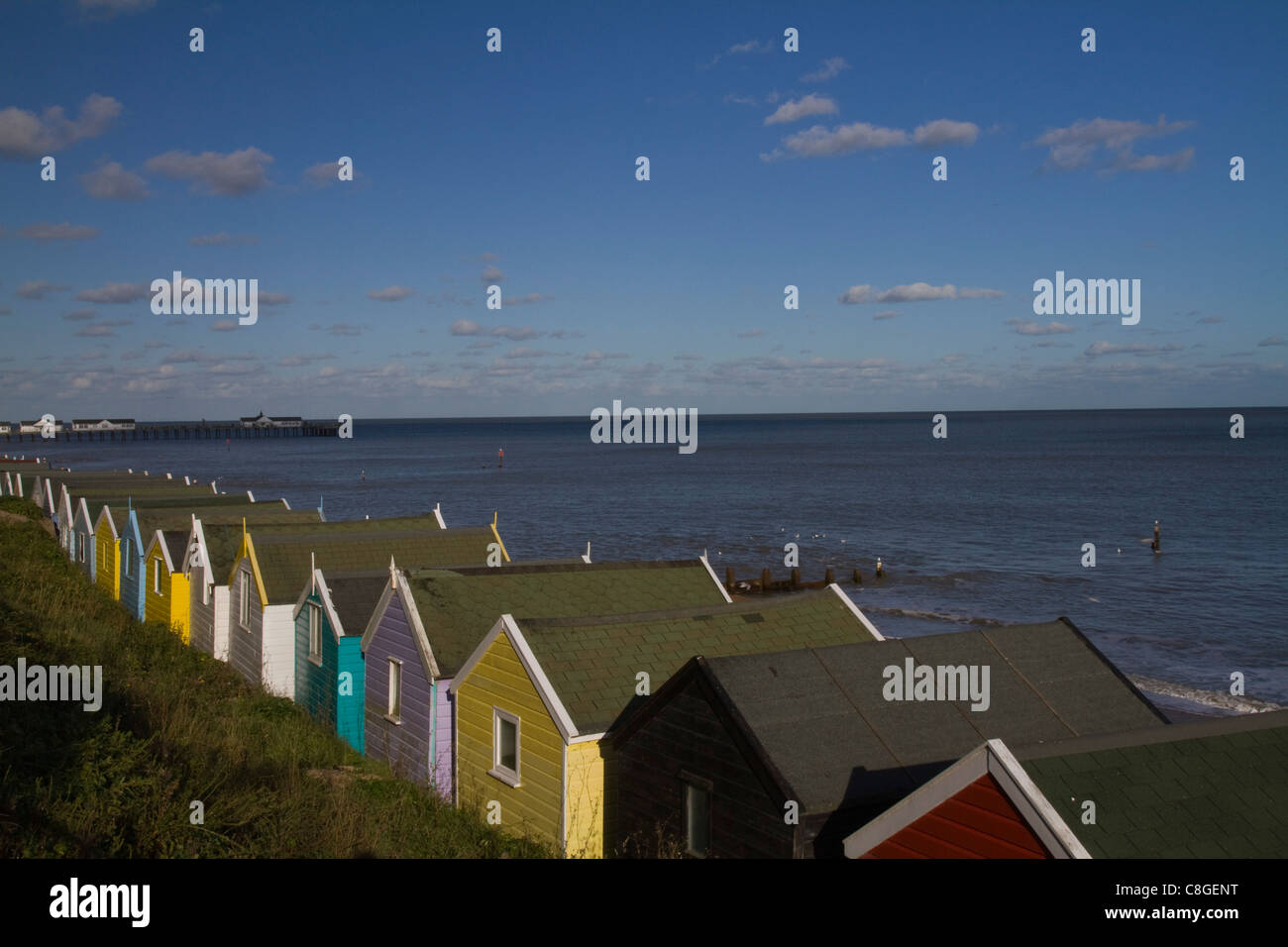 Colourful beach huts look out over the sea under a bright blue sky at ...