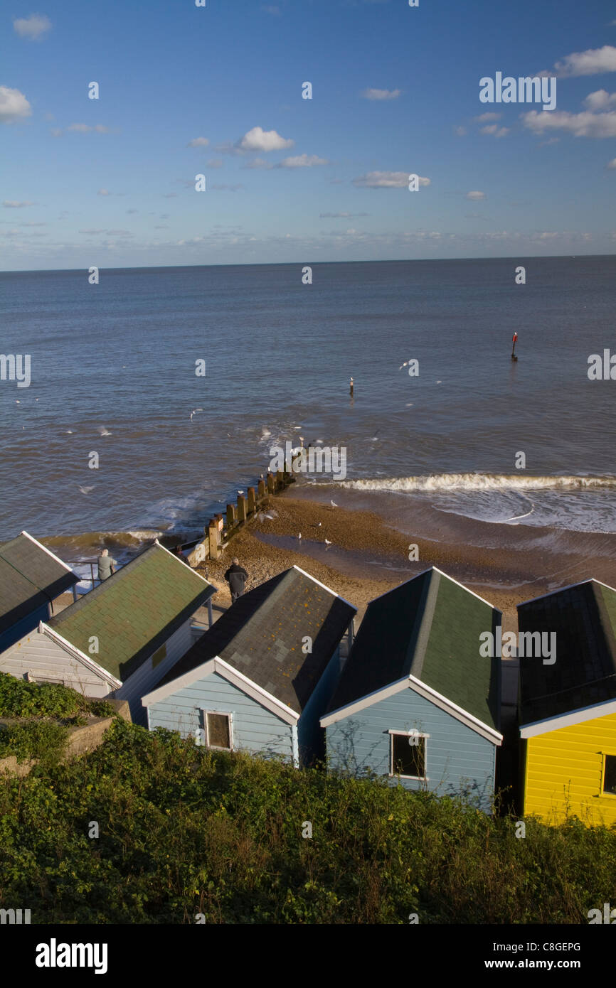 Colourful beach huts look out over the sea under a bright blue sky at ...