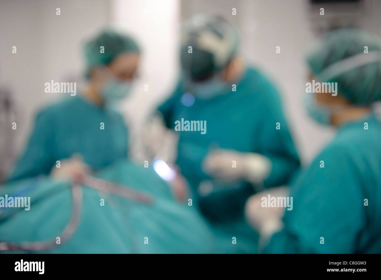 Three blurred doctors performing surgery in hospital operating room ...
