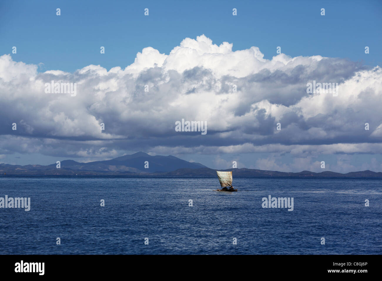 A traditional malagasy pirogue or outrigger canoe with a patched sail ...