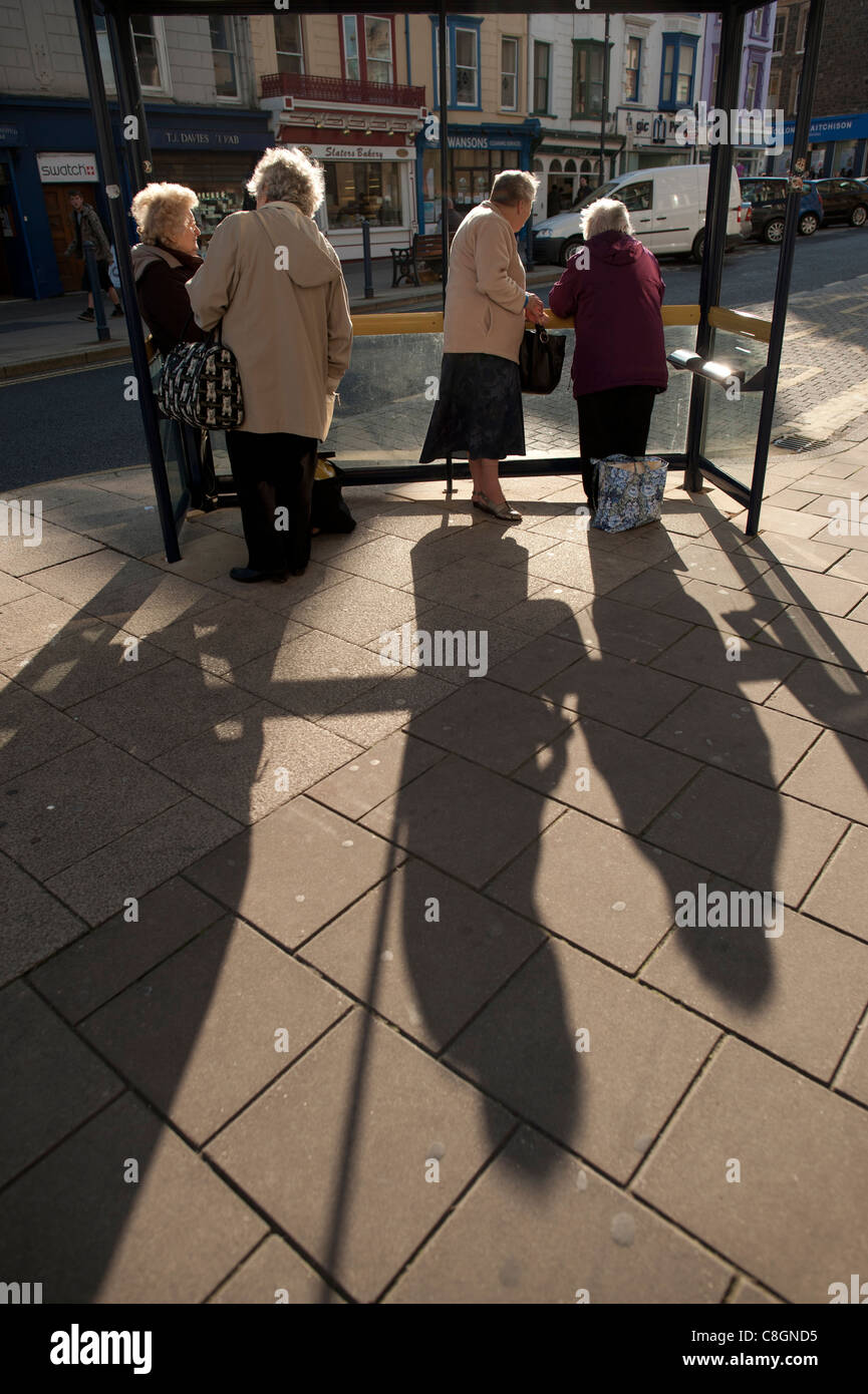 Four old senior elderly retired pensioner women at a bus stop waiting ...