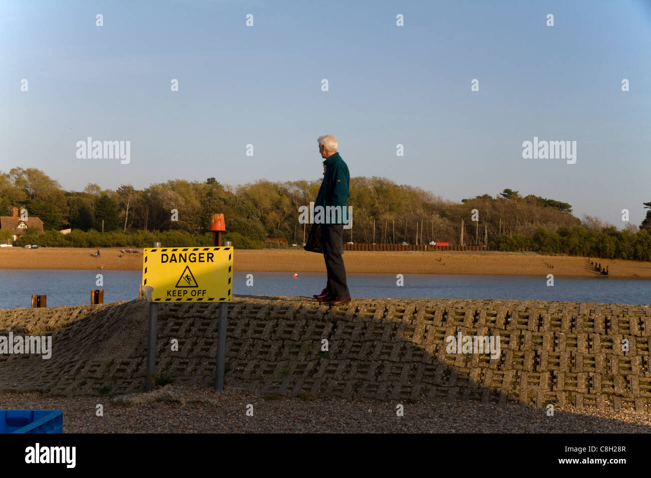 A couple stand on sea defences next to a 'Danger Keep Off' sign at ...