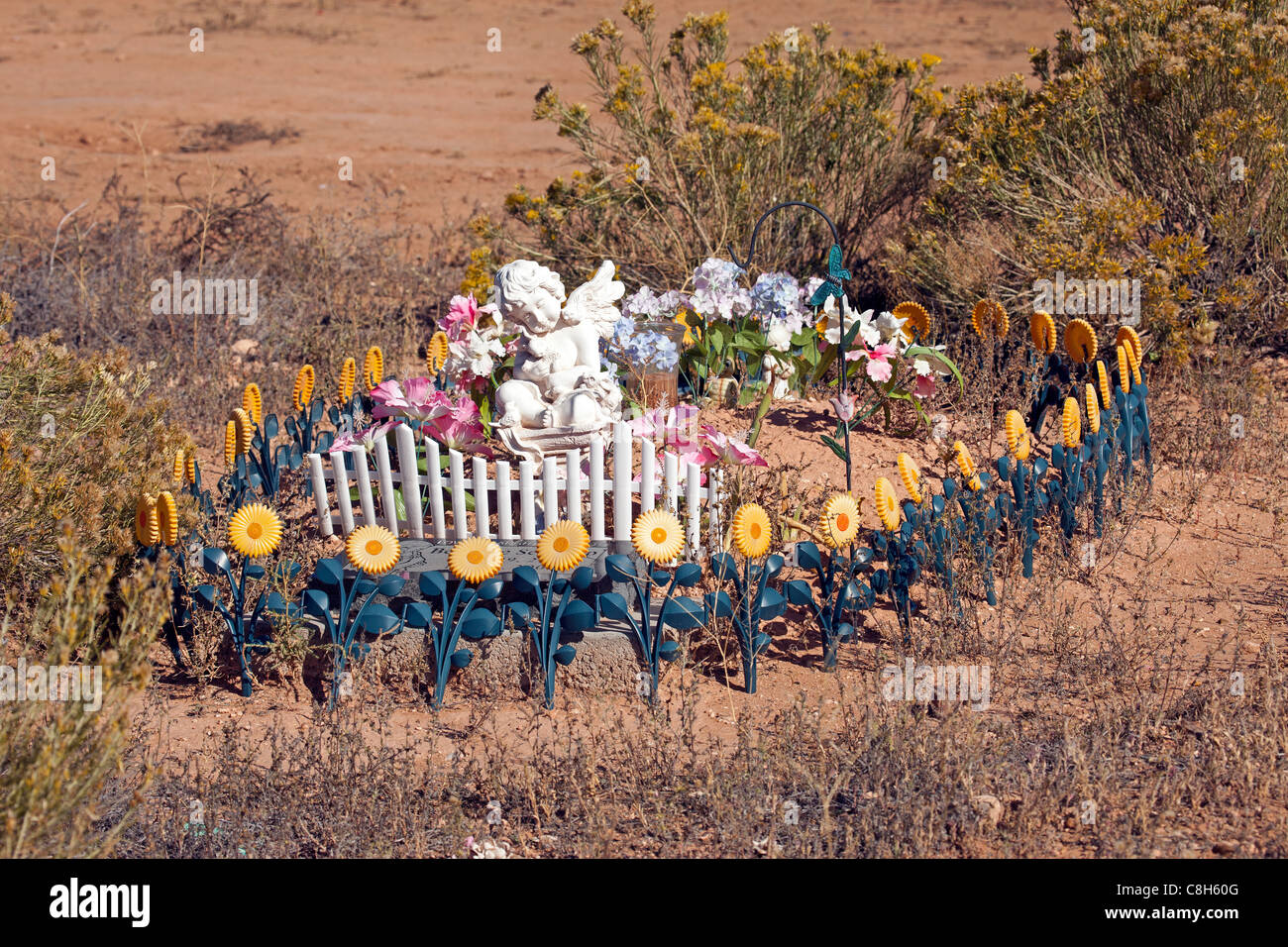 Cemetery neglected, overgrown with weeds with angel, plastic flowers ...