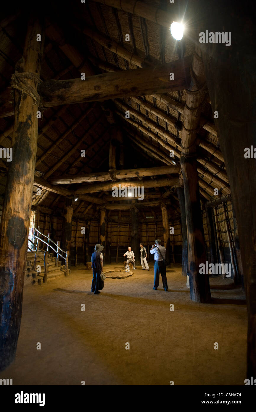 Visitors look at the interior of a reconstruction of a long house ...