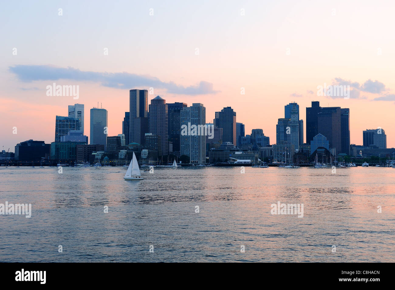 Boston downtown sunset skyline over river with skyscrapers and boat ...