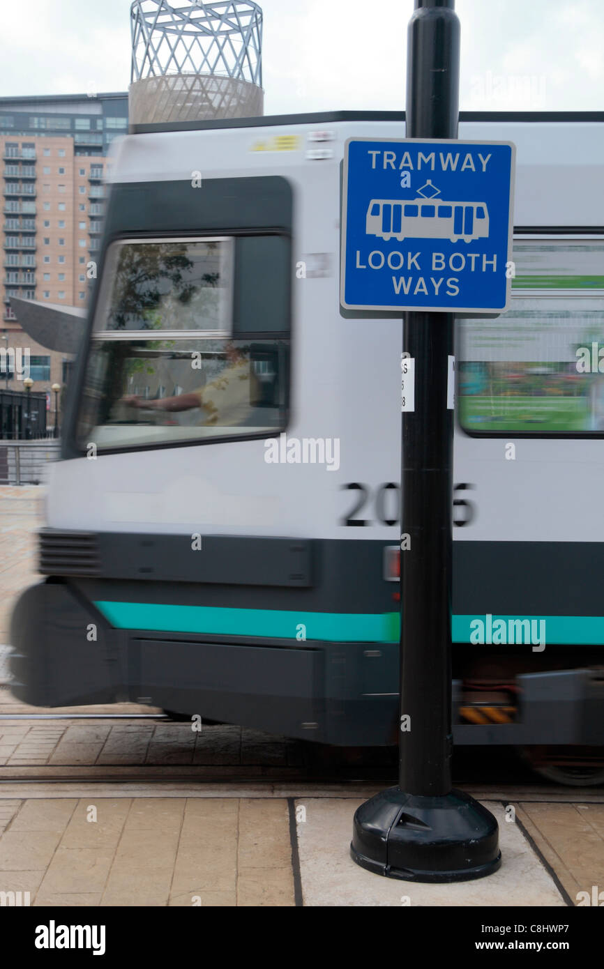 Manchester Metrolink tram moving past a "Look Both Ways" tram sign ...