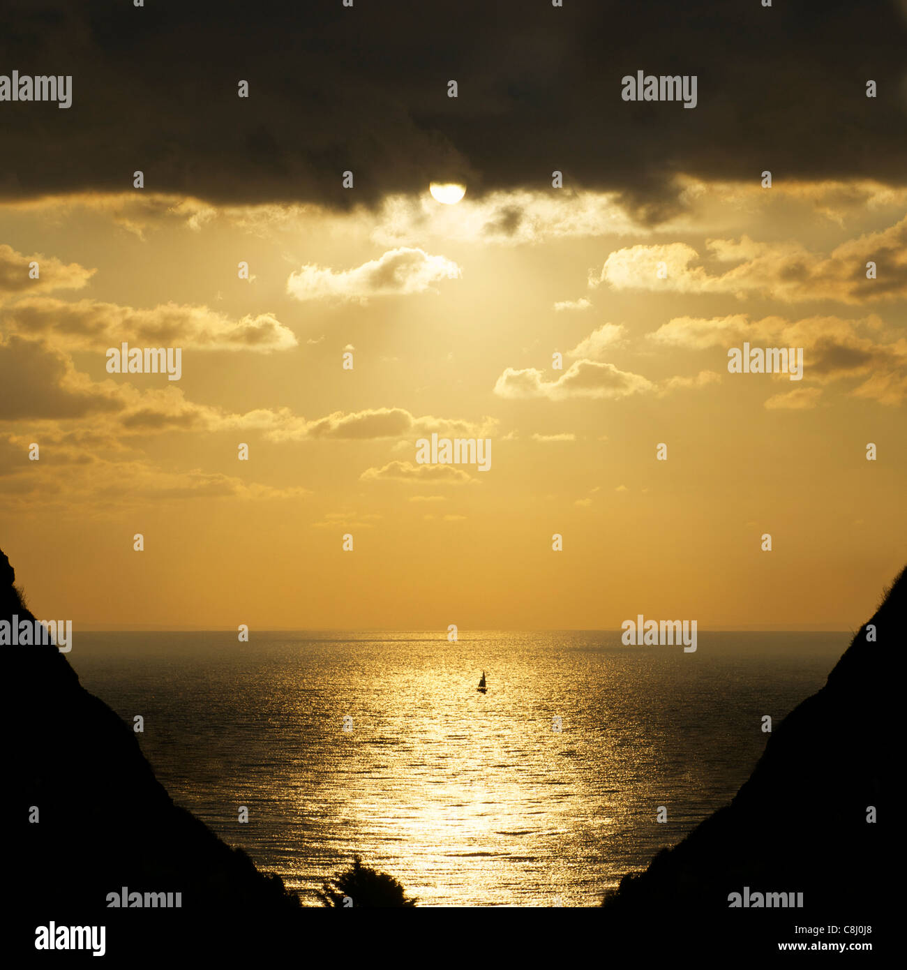 A yacht sailing into the sunrise off the East Coast of Devon, England ...