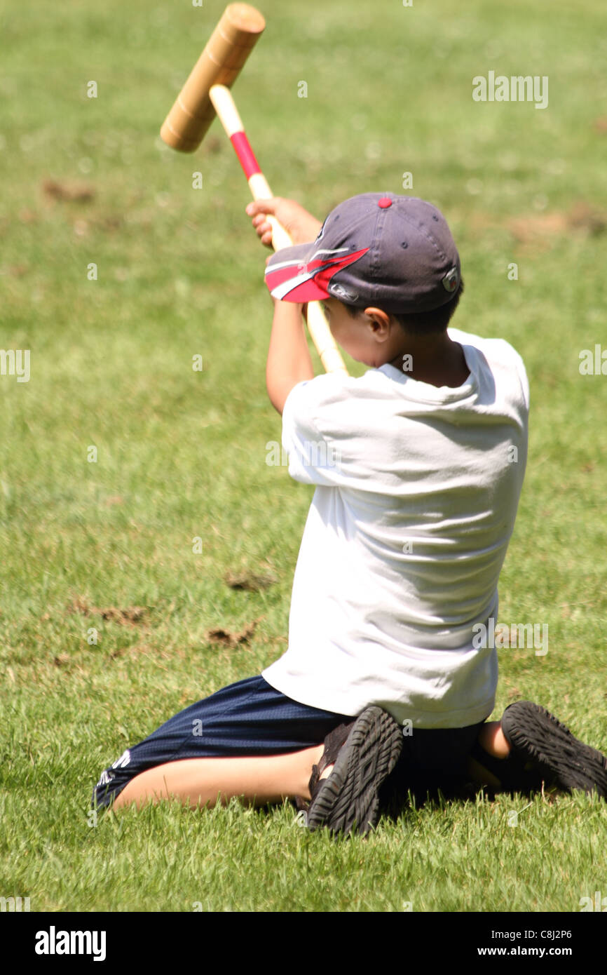 Croquet game boy playing action with pallet on knees Stock Photo - Alamy