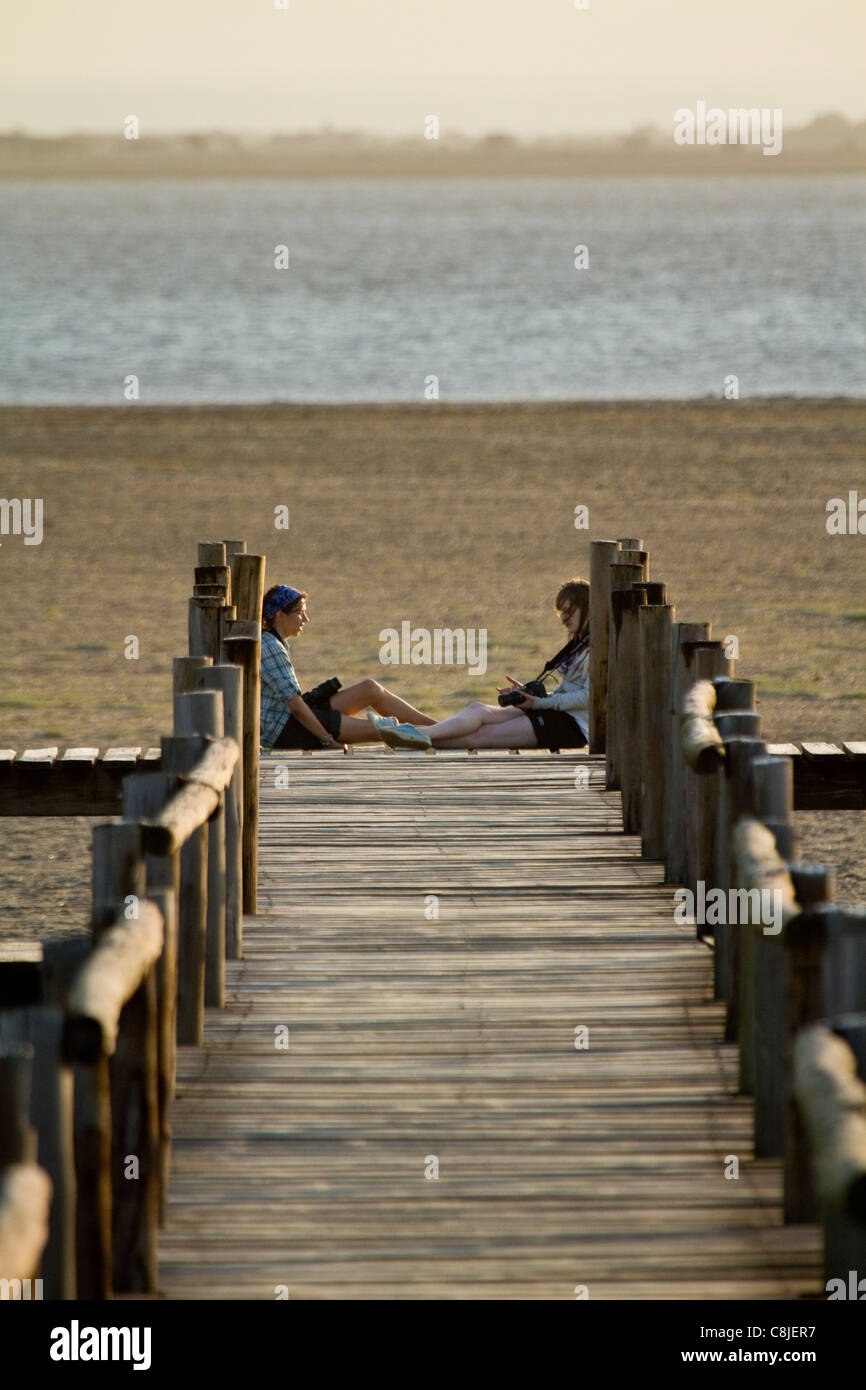 Two people relaxing on the end of a jetty Stock Photo - Alamy