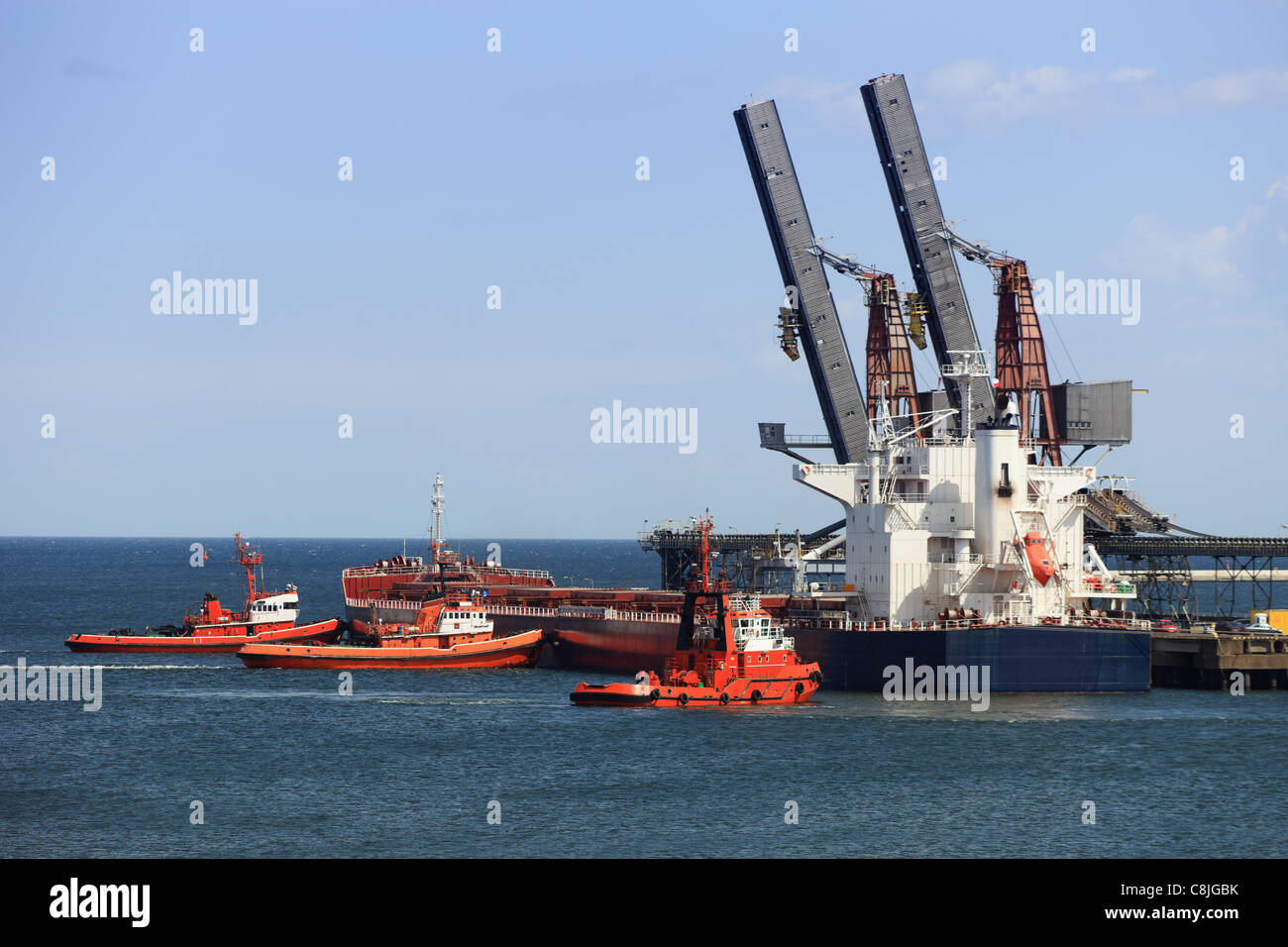Tugboat pushing on a cargo ship in port Stock Photo - Alamy