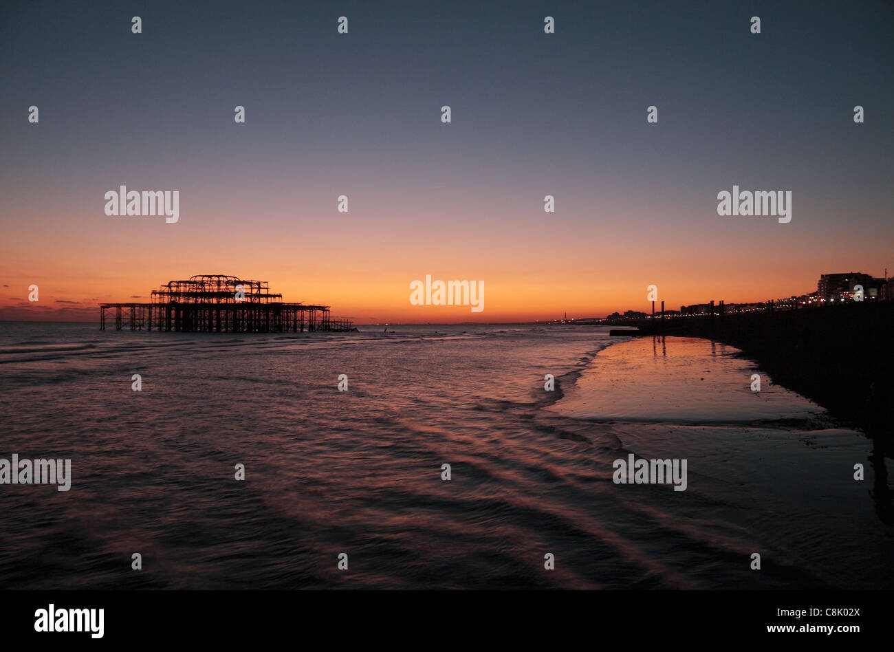 Sunset view along Brighton beach, East Sussex, UK towards the ruins of ...