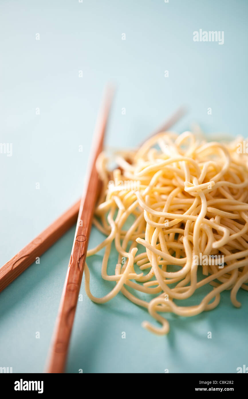 Noodles and chop sticks on pale blue table Stock Photo - Alamy