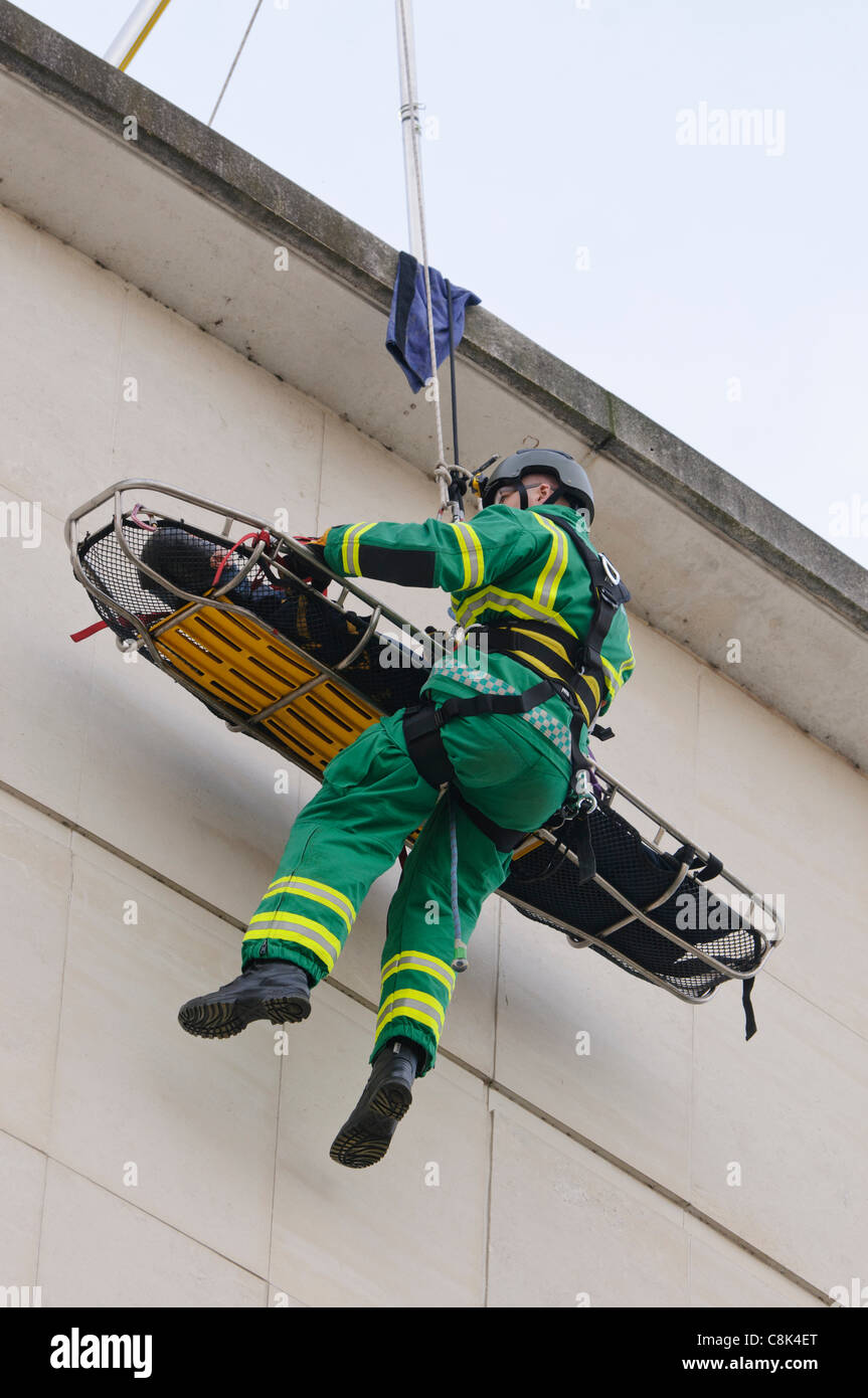 Paramedic is winched down a building on a rope with a patient during ...