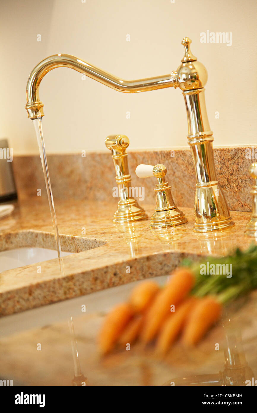 Gold Mixer tap running water in a kitchen Stock Photo - Alamy