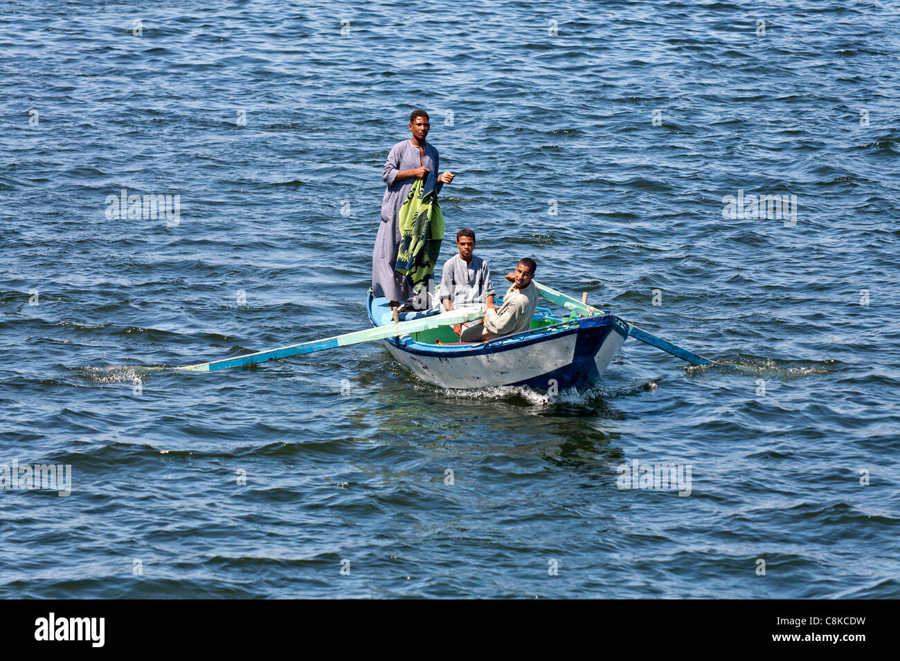 Three market traders rowing a small blue boat in Esna lock Egypt ...