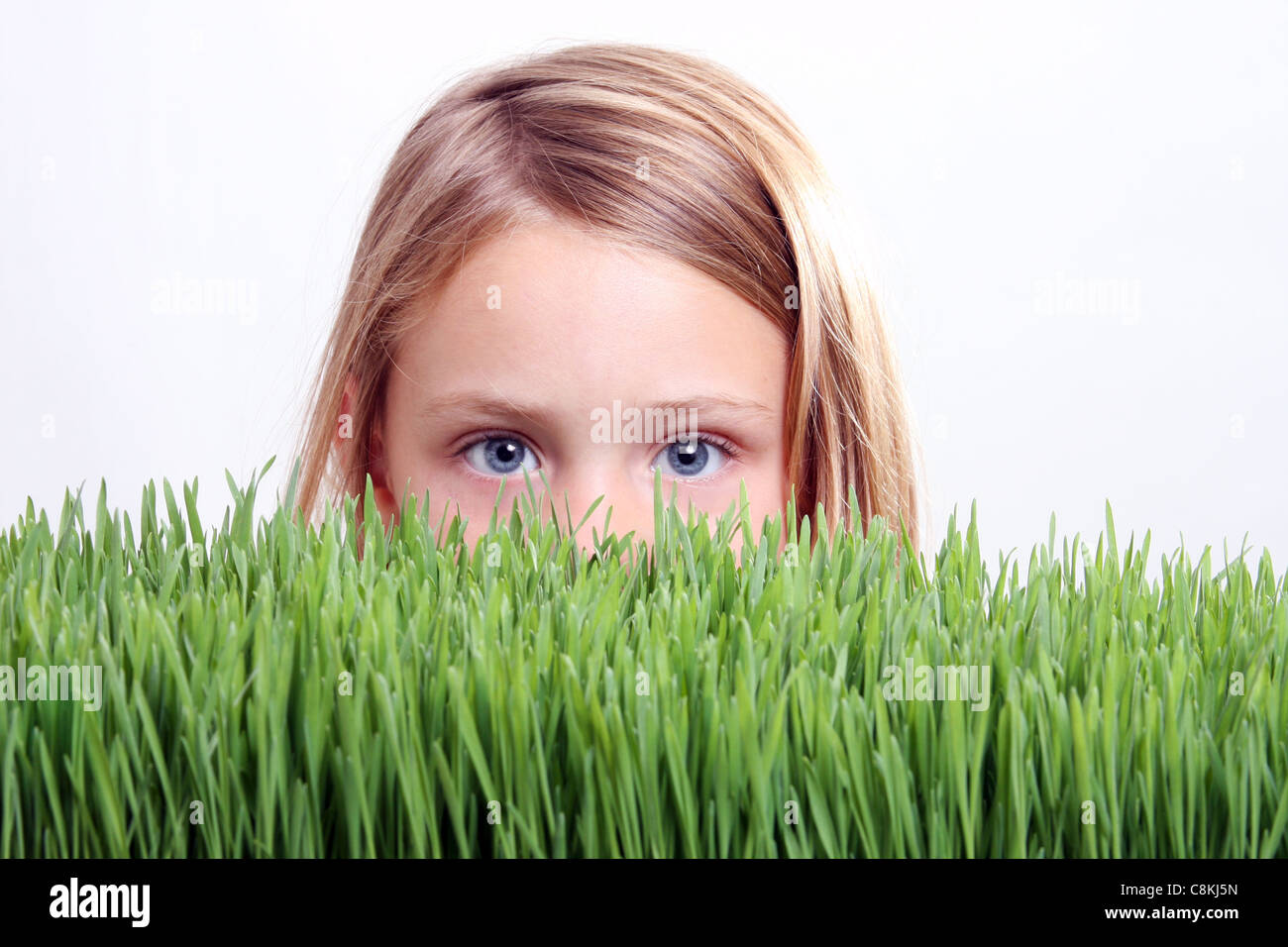 A young female child looking above blades of grass Stock Photo - Alamy