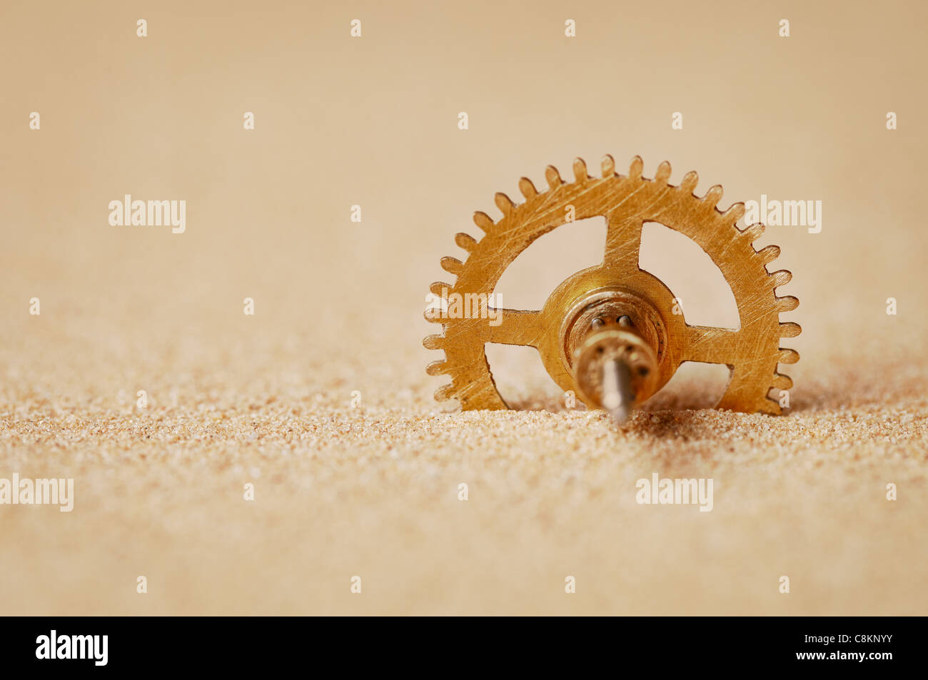 Clock detail - a gear in the sand close up Stock Photo - Alamy